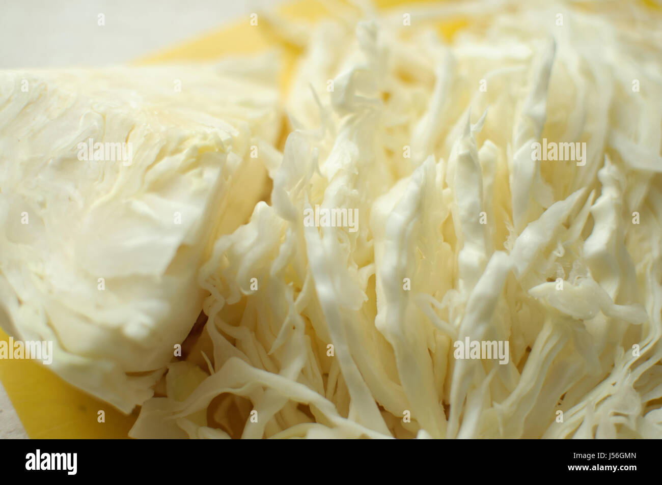 Sliced white cabbage on a yellow cutting board close up. Selective ...