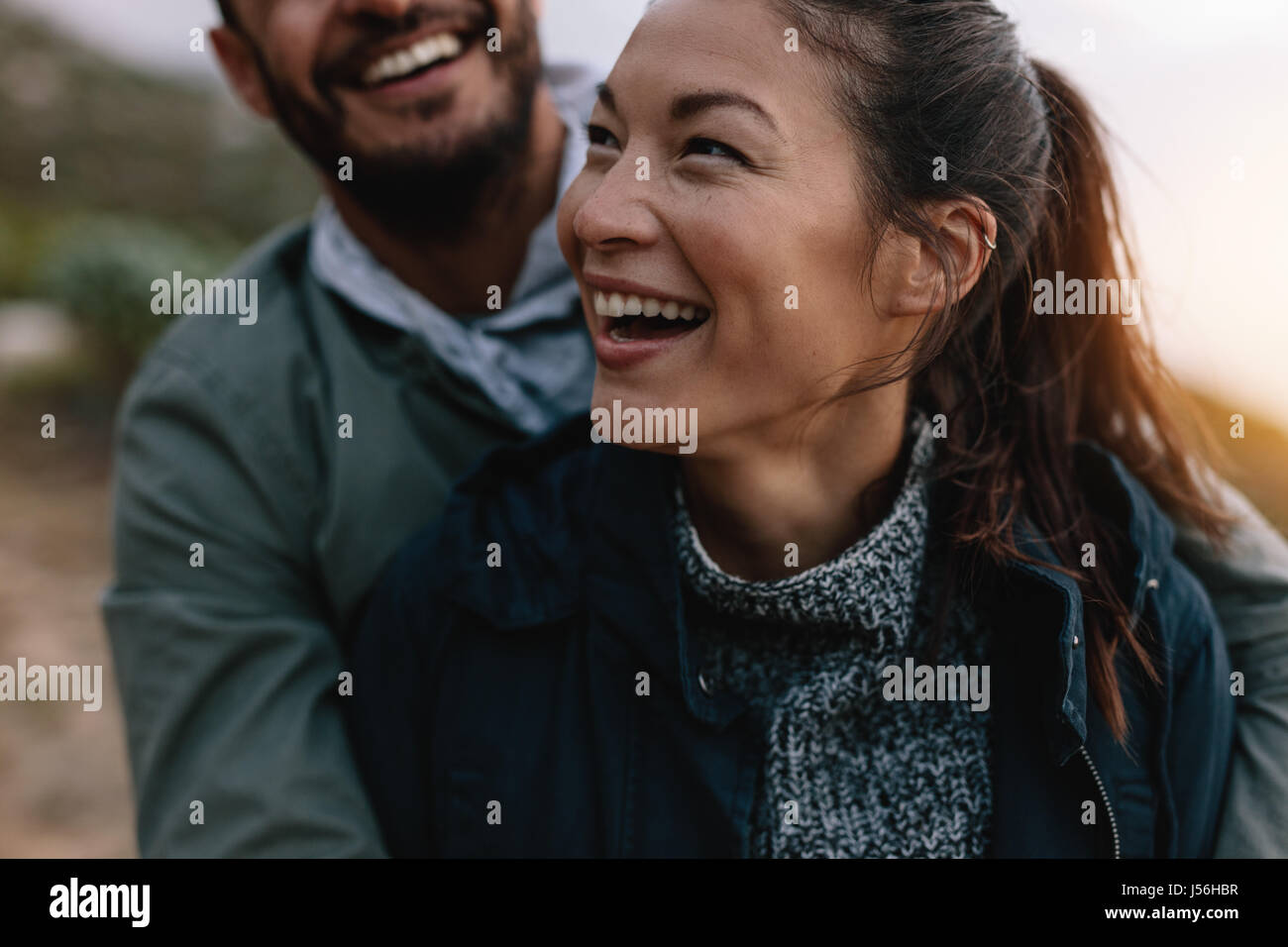 Smiling asian woman being embraced by her boyfriend from behind. Couple ...