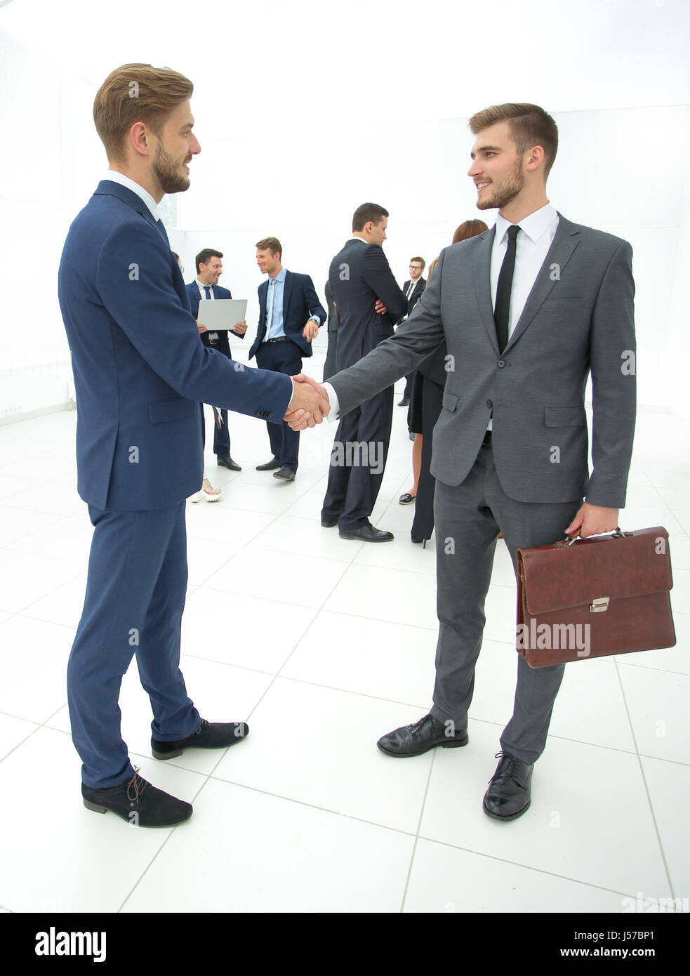 Two businessmen making agreement, their colleagues standing near Stock ...