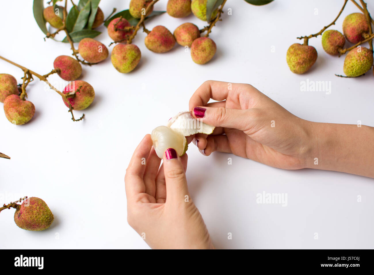 Female hands peeling lychee fruit on white Stock Photo - Alamy