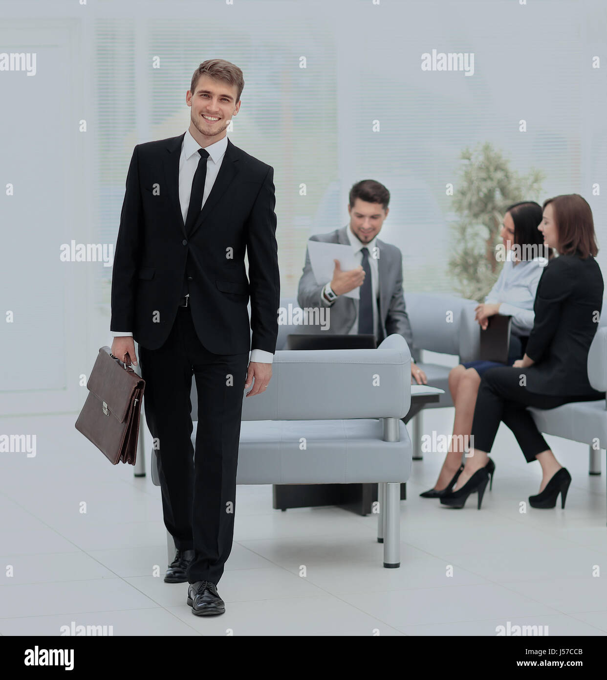 Successful business man standing with his staff in background at Stock ...