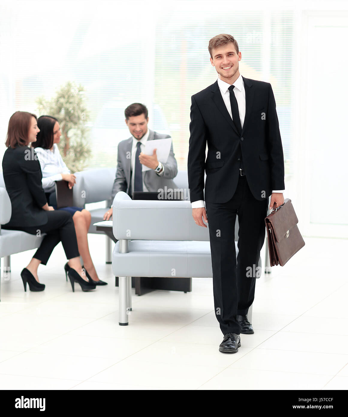 Successful business man standing with his staff in background at Stock ...