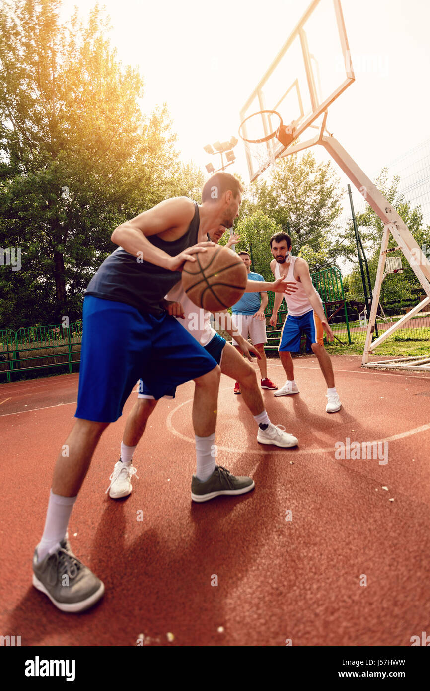 Four basketball players have a training outdoor. They are playing and ...
