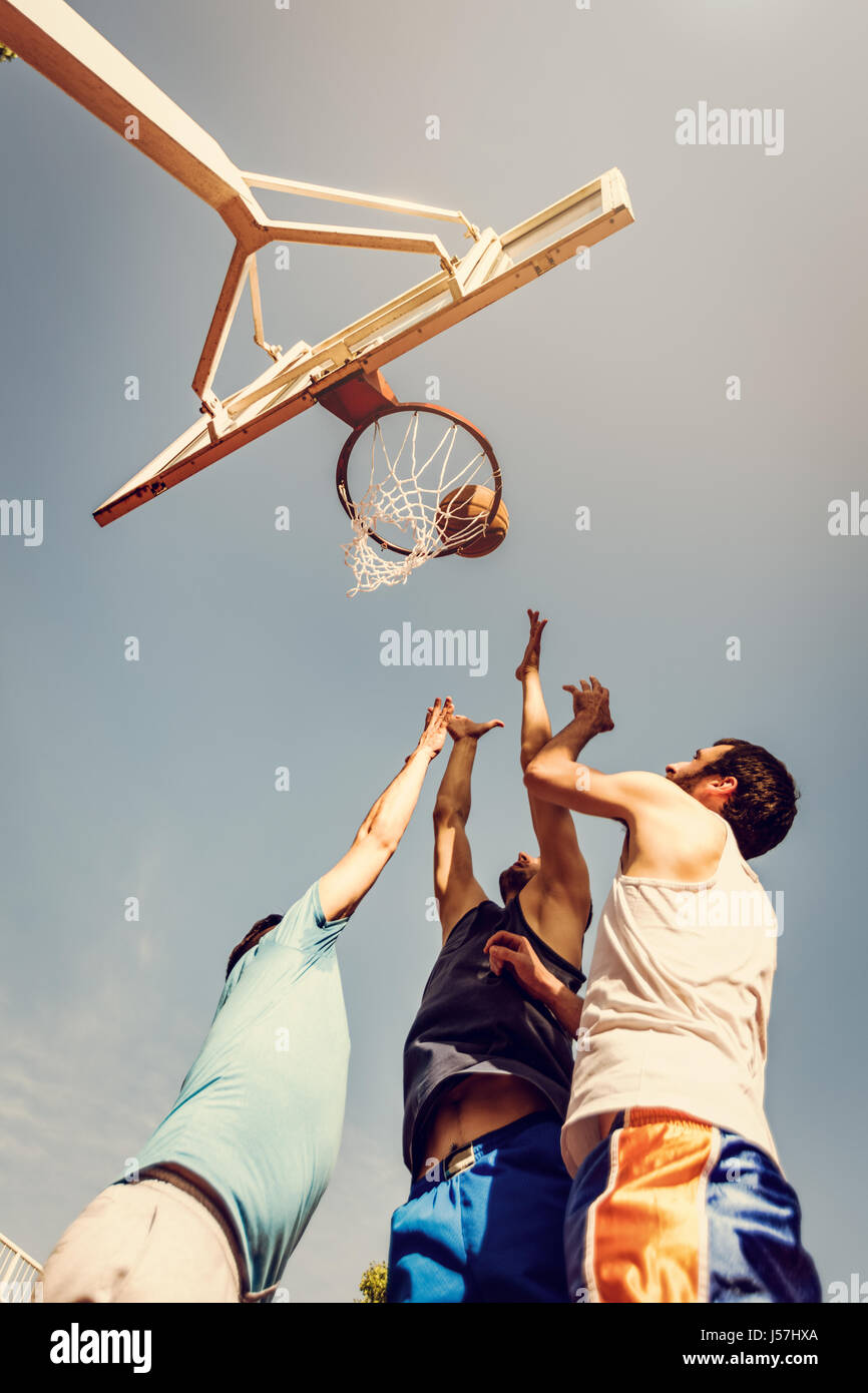 Four basketball players have a training outdoor. They are playing and ...