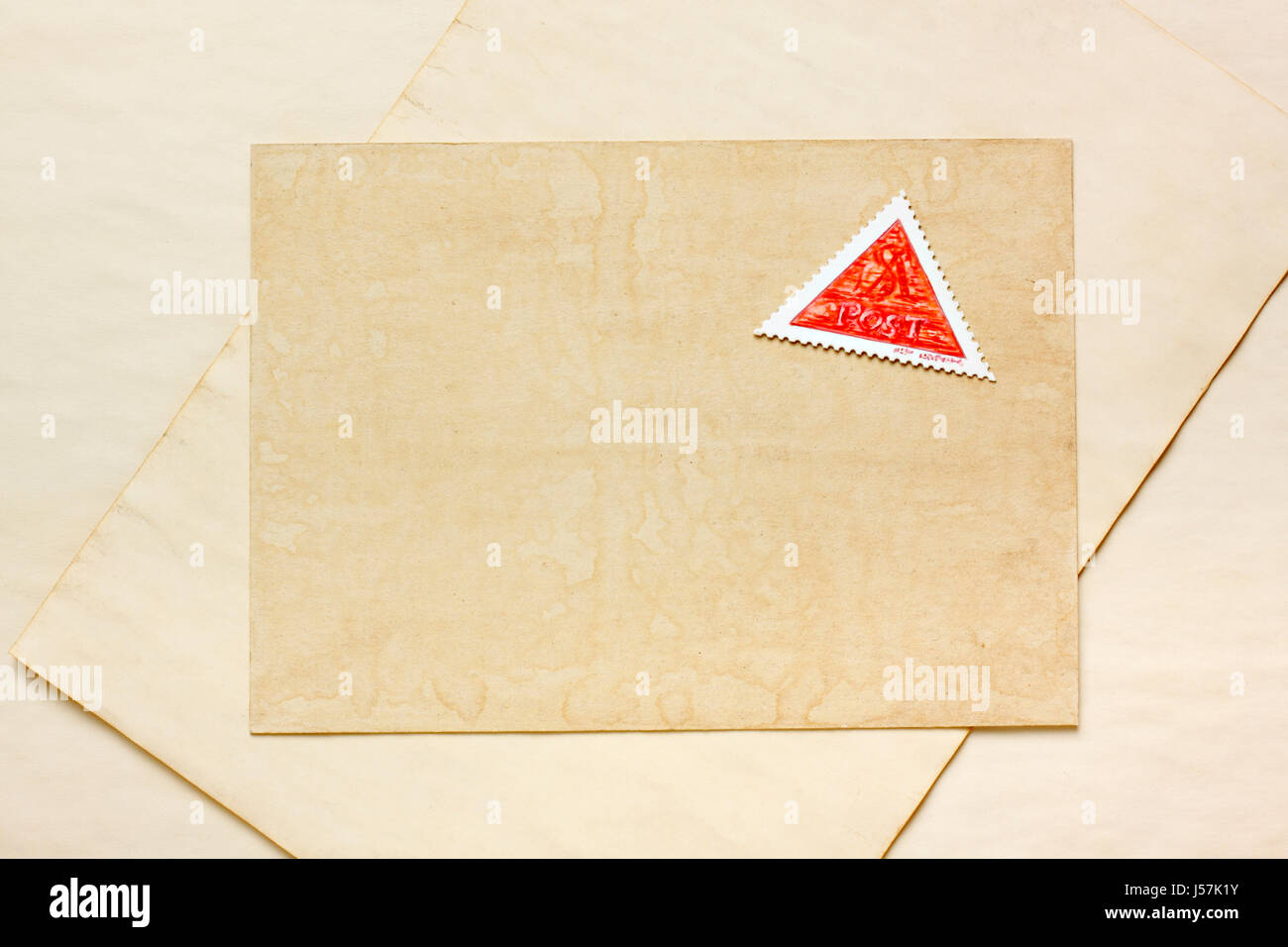 Aged empty card with painted abstract triangle postage stamp over aged ...