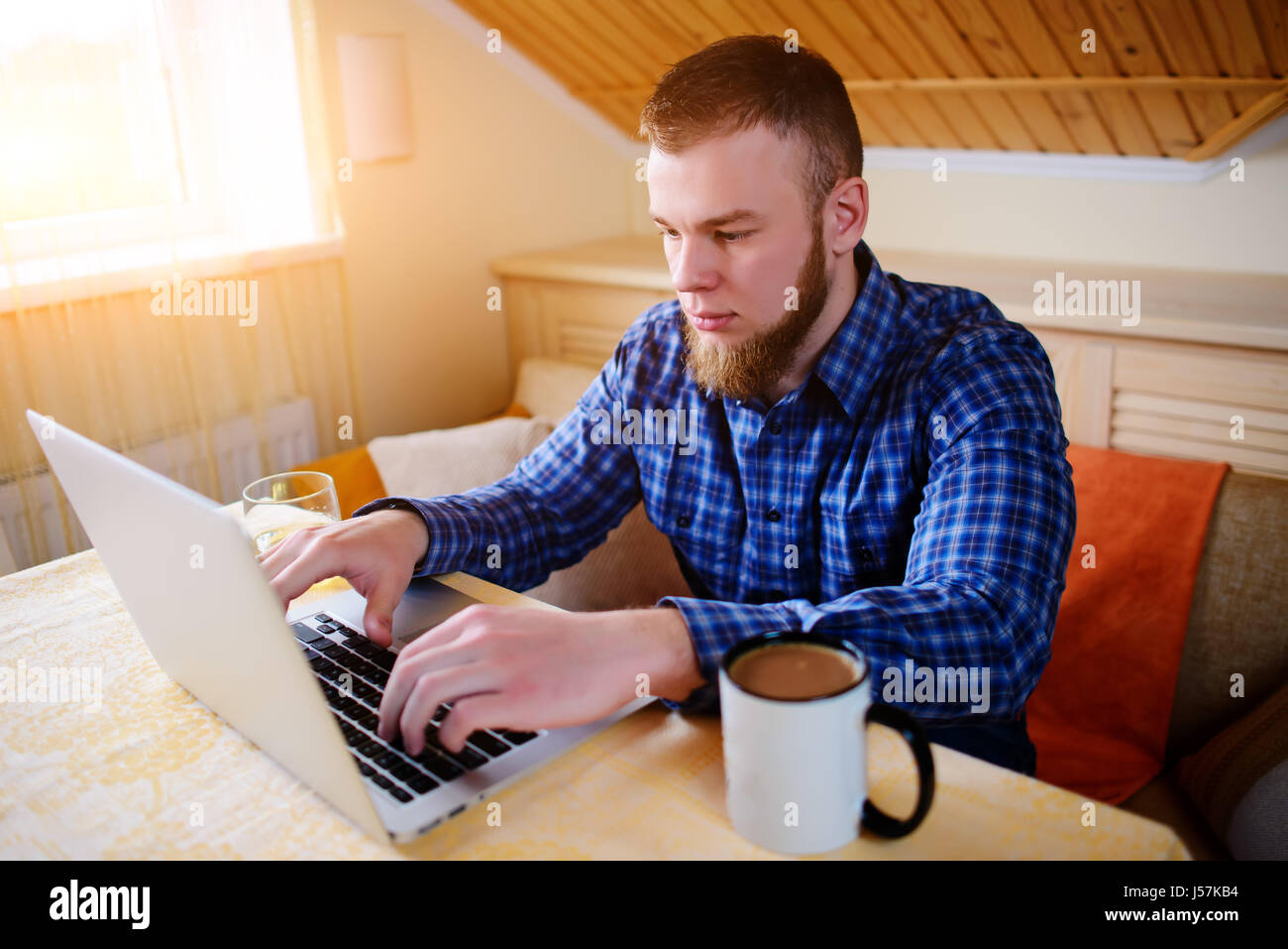 Relaxed young professional surfing the Internet on his laptop in a a ...