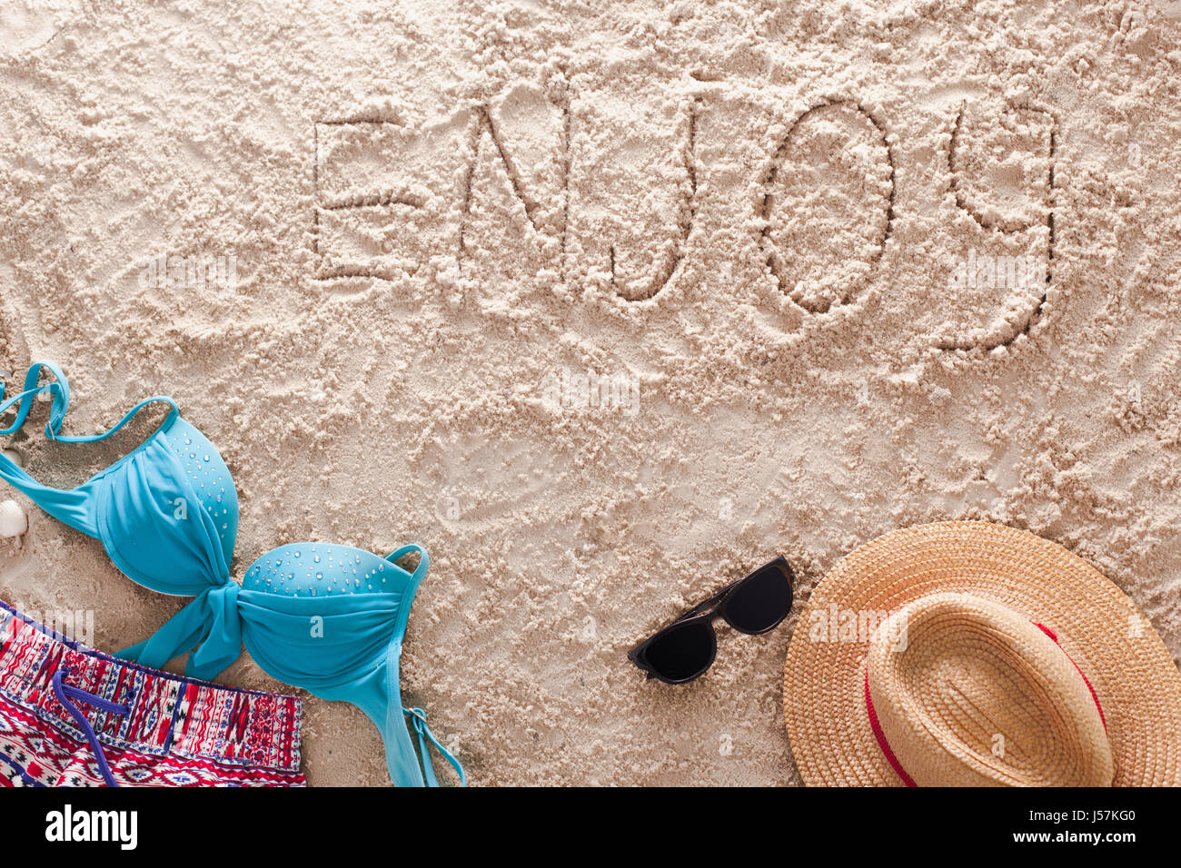 Enjoy written in a sandy tropical beach Stock Photo - Alamy
