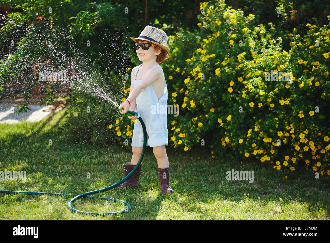 cute little boy watering the garden with hose Stock Photo - Alamy