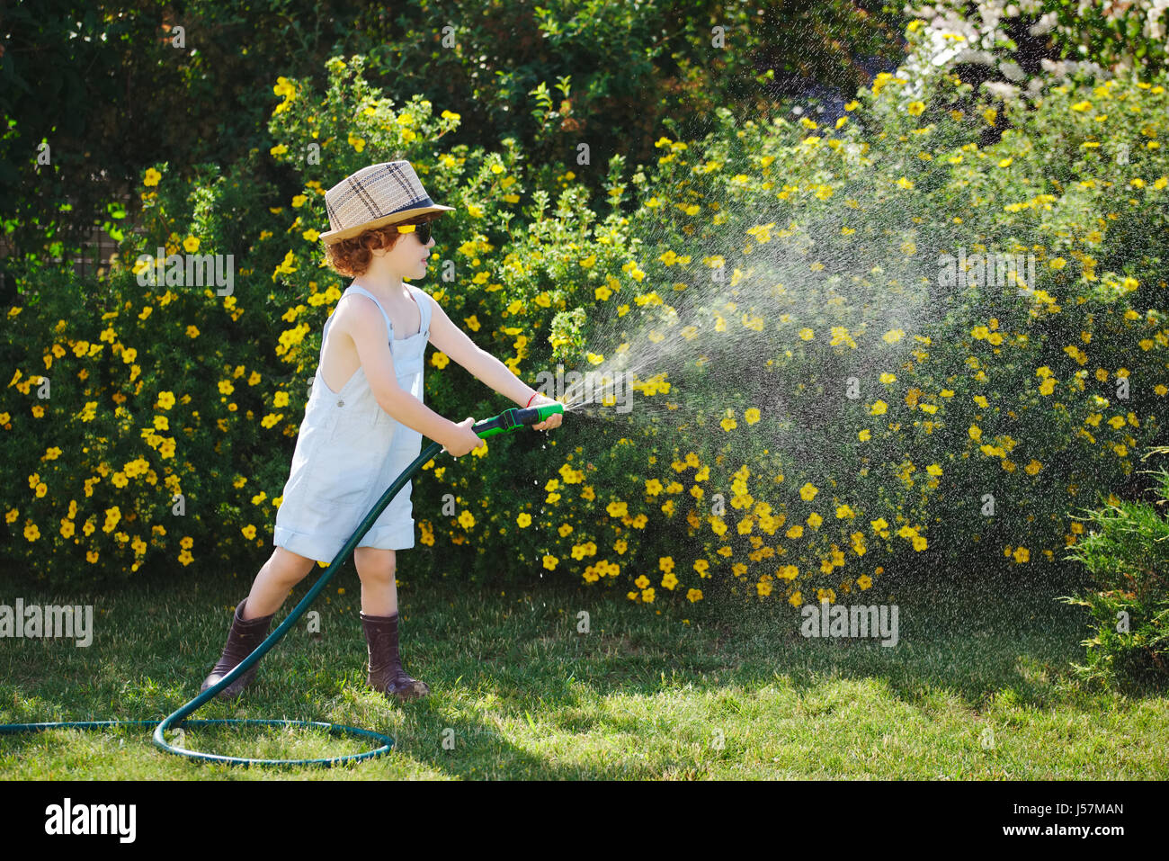 cute little boy watering the garden with hose Stock Photo - Alamy