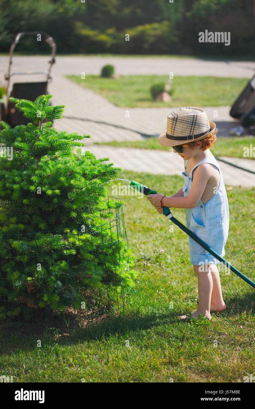 cute little boy watering the garden with hose Stock Photo - Alamy