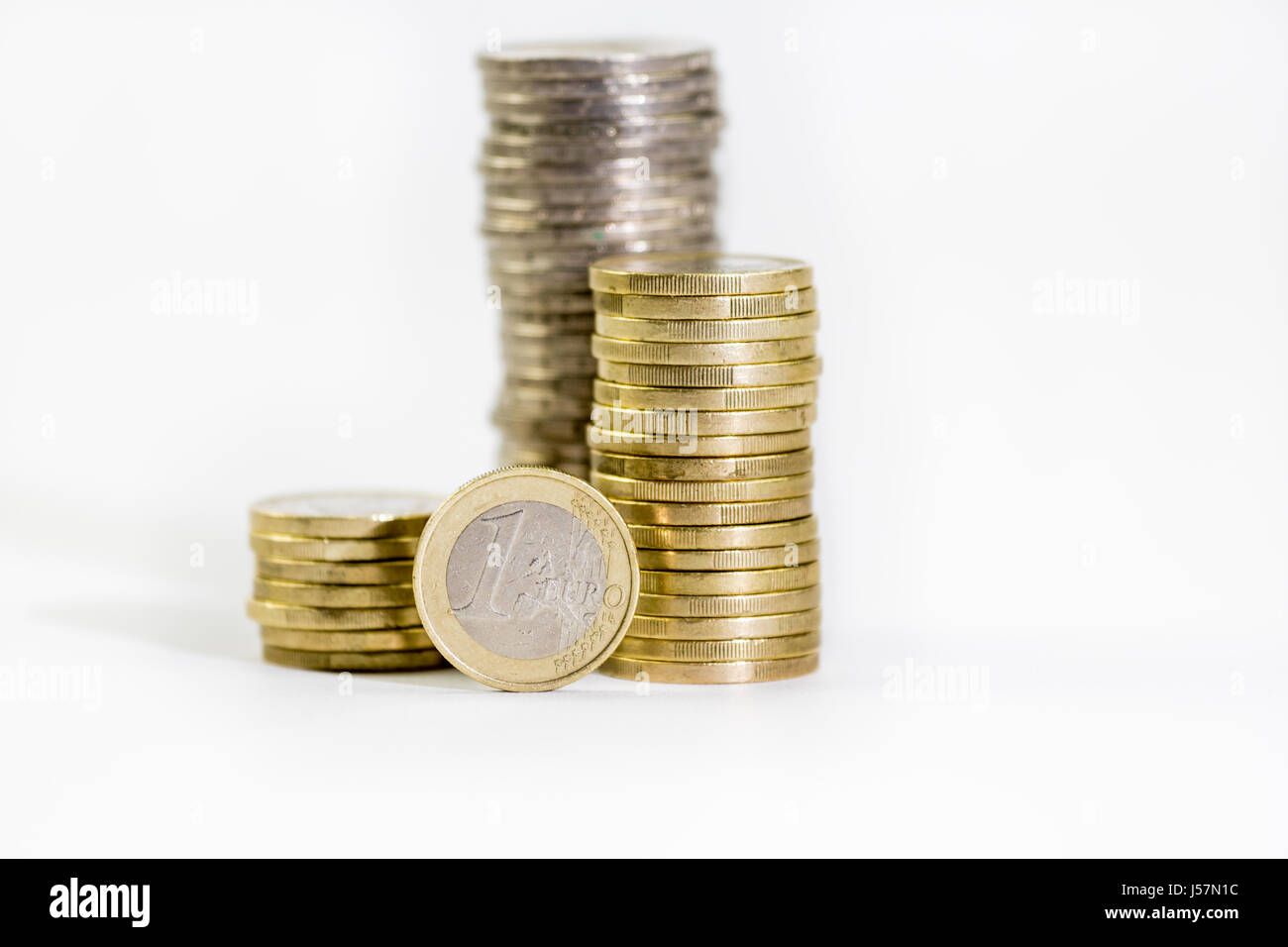 coins of 2 and 1 euros stacked and euro banknotes on a white background ...