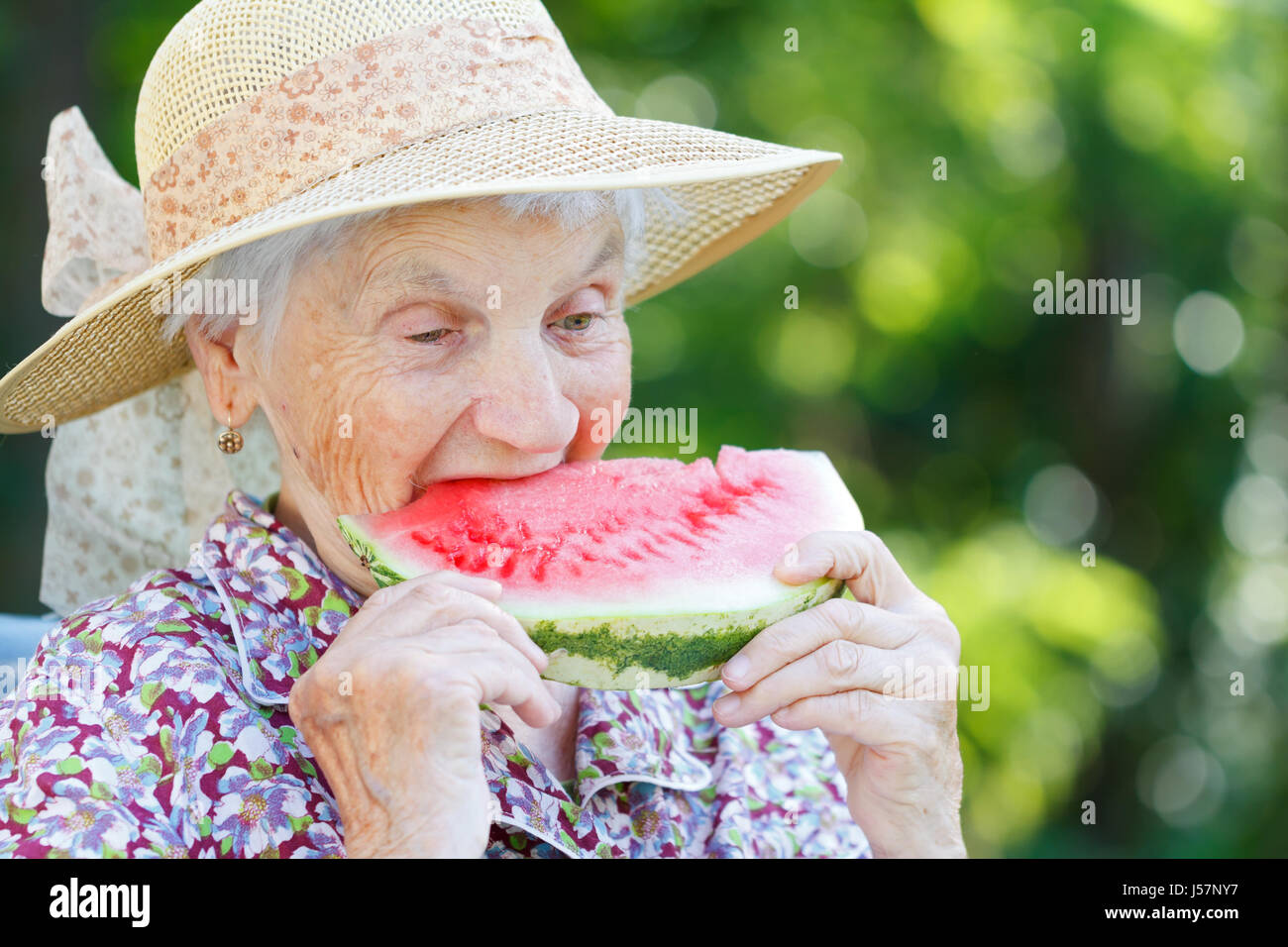 Happy elderly woman eating watermelon in the garden Stock Photo - Alamy