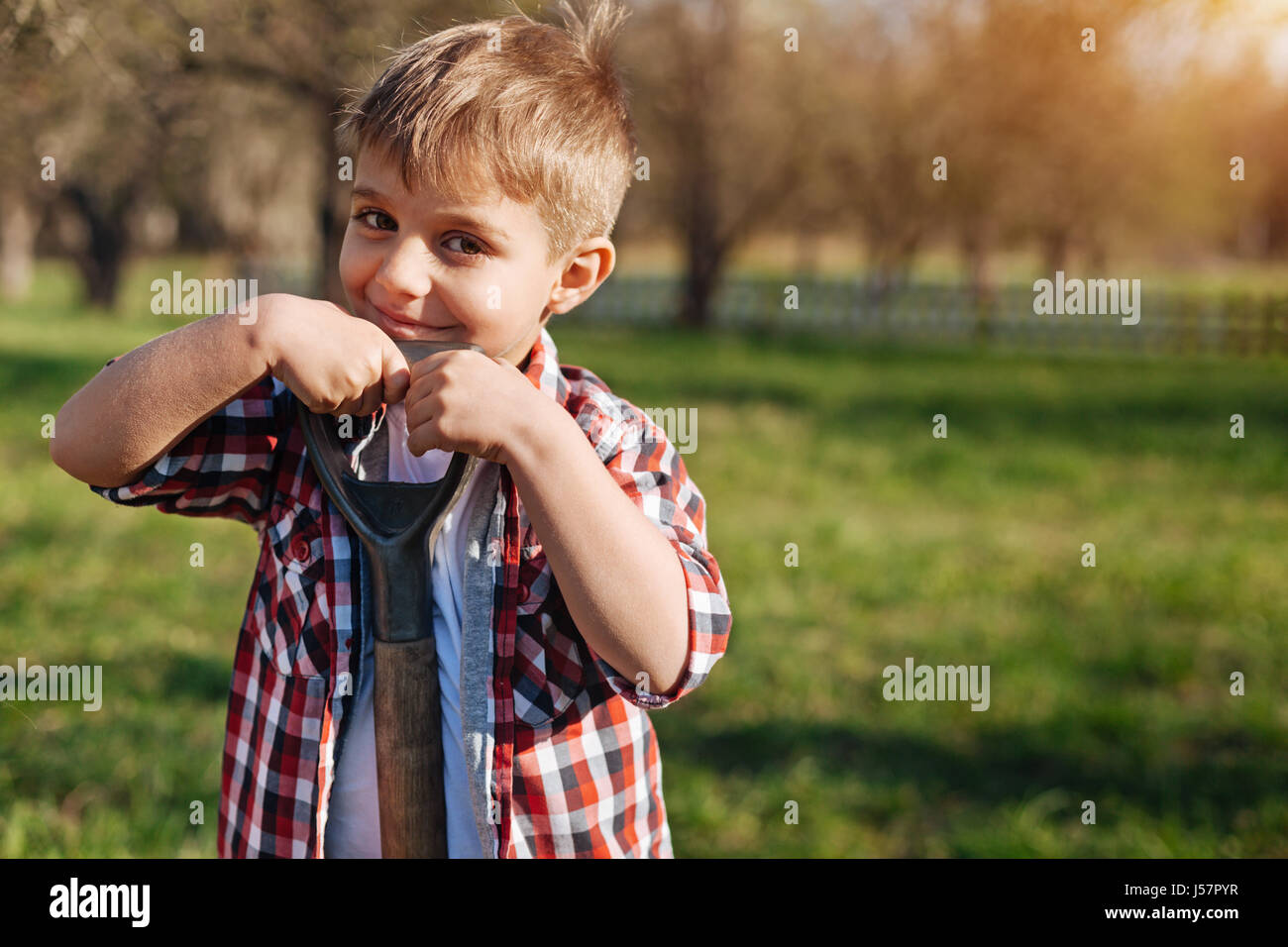 Smiling chestnut haired boy with spade in garden Stock Photo - Alamy