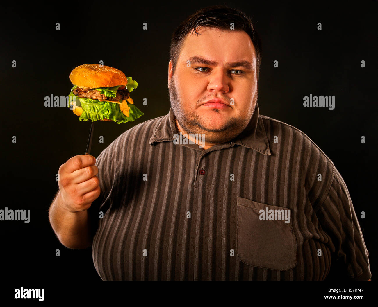 Fat man eating fast food hamberger. Breakfast for overweight person ...