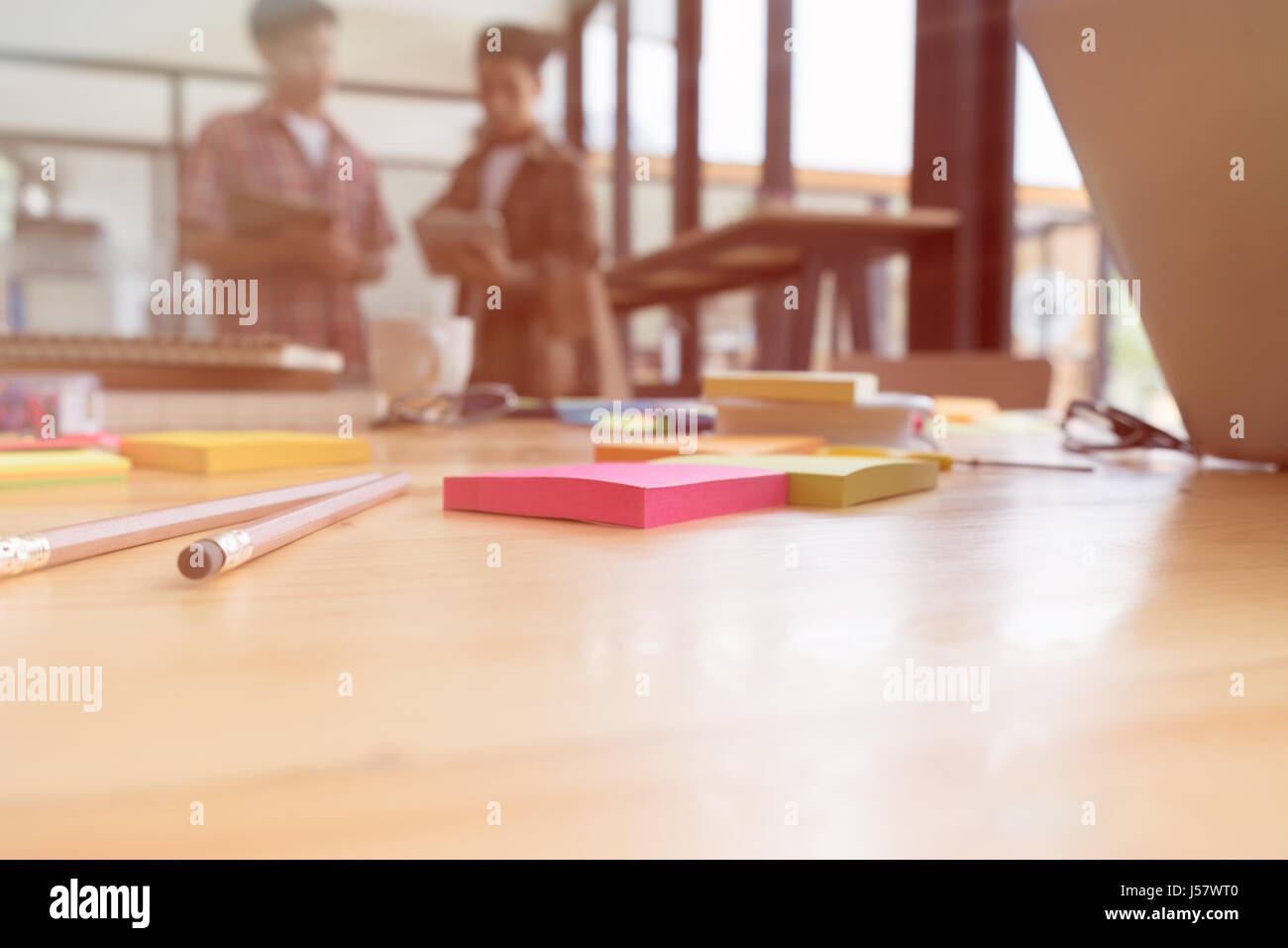 pencil and sticky note on table with background of young university ...