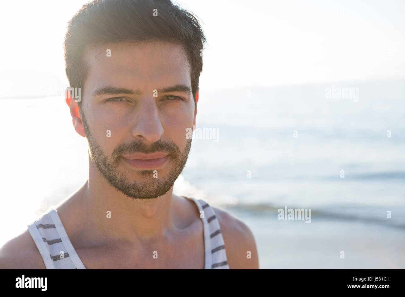 Portrait of young man at beach on sunny day Stock Photo - Alamy