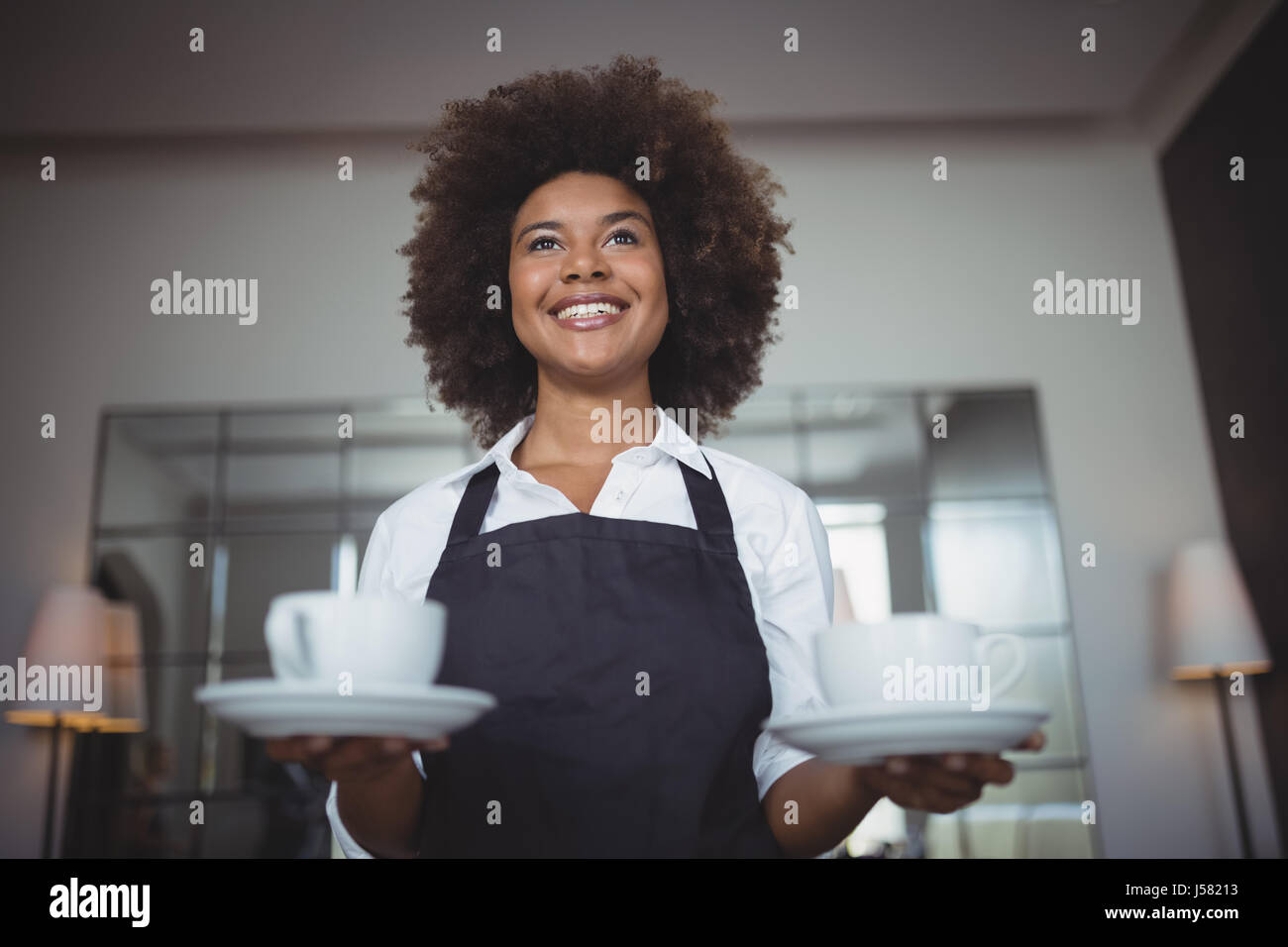 Smiling waitress holding coffee in restaurant Stock Photo - Alamy