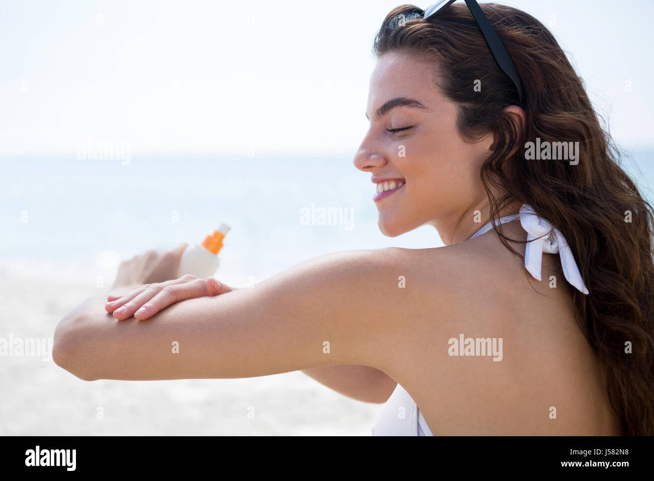 Side view of woman applying sunscream on arms at beach Stock Photo - Alamy