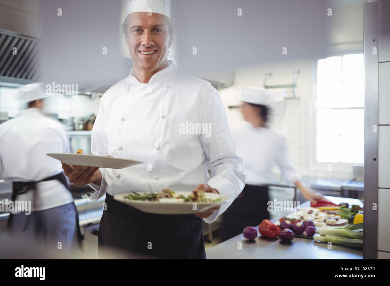 Portrait of chef presenting his food plates in the commercial kitchen ...