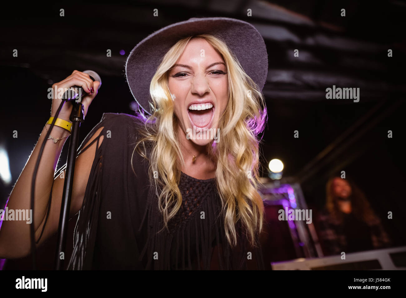 Portrait of cheerful female singer performing at nightclub during music ...