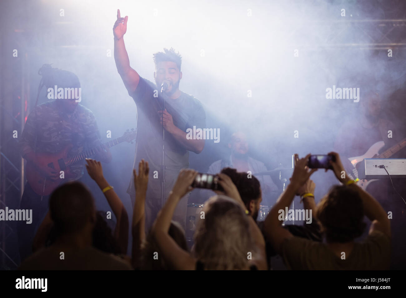 Fans photographing male singer performing at nightclub during music ...