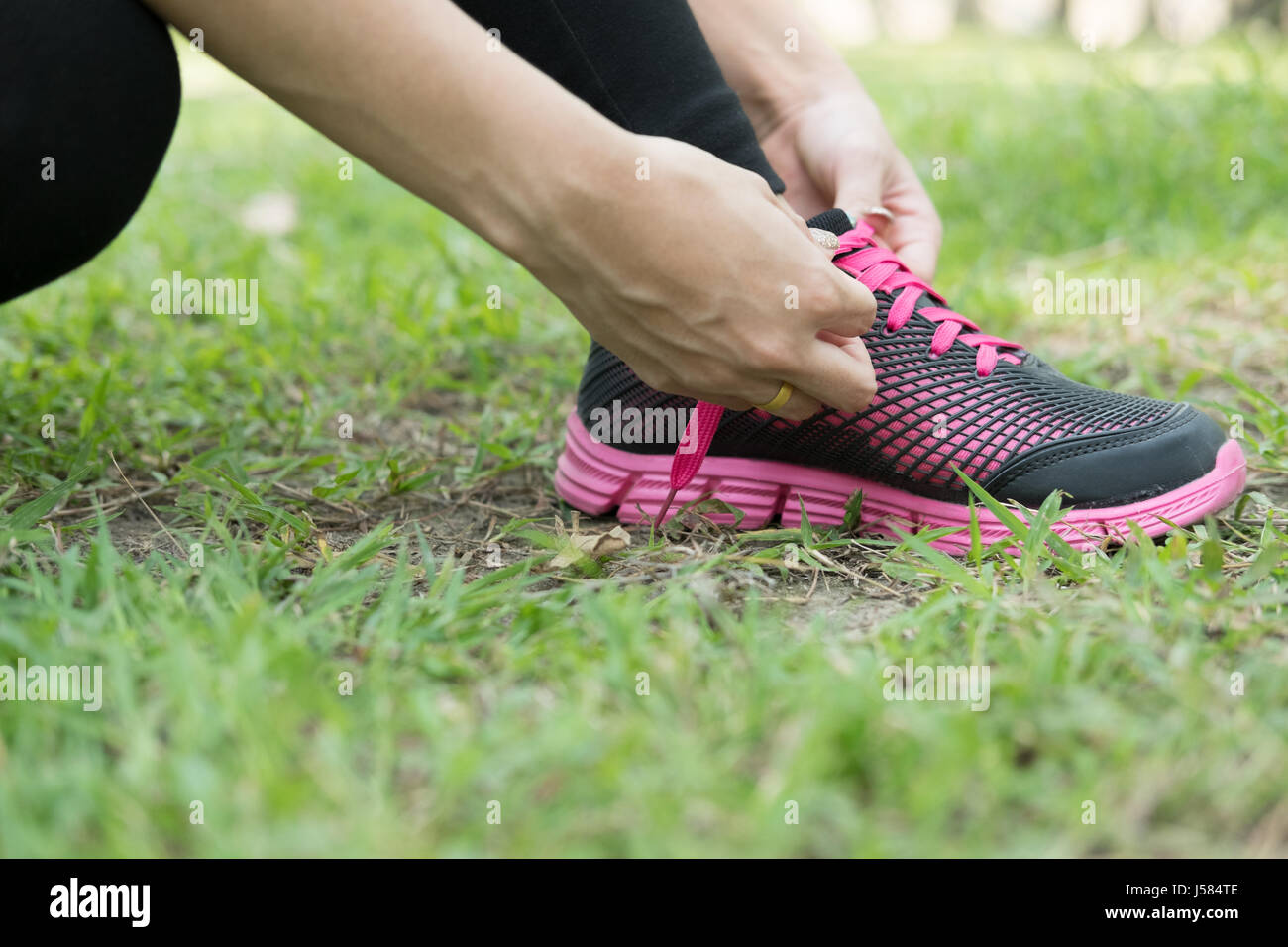 Urban athlete woman tying running shoe laces. Female sport fitness runner getting ready for ...