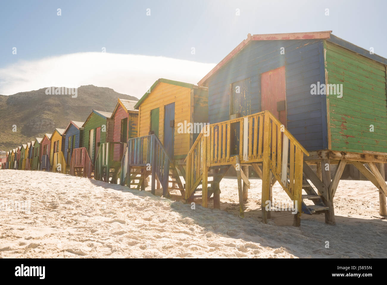 Colorful huts on sand against mountain at beach Stock Photo - Alamy