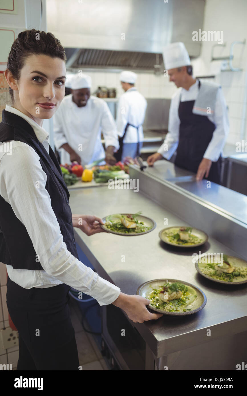 Waitress showing dishes to the camera and team of chefs working in ...
