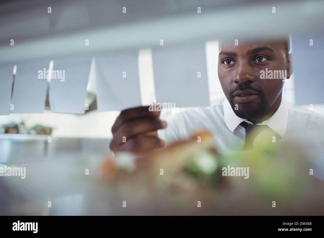 Chef looking at an order list in the commercial kitchen at restaurant ...