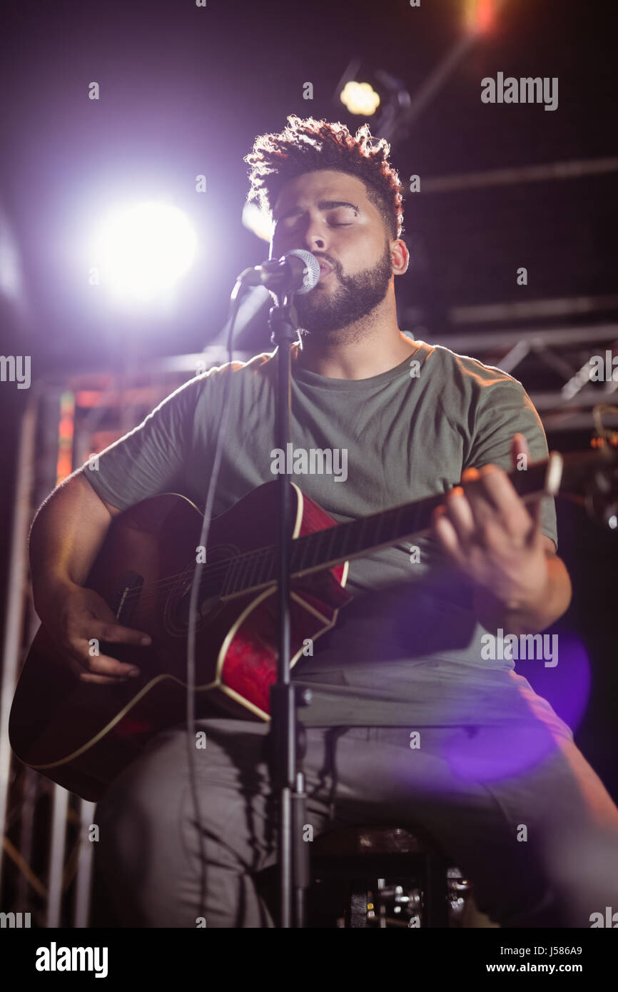 Male musician with eyes closed singing on stage at nightclub Stock ...