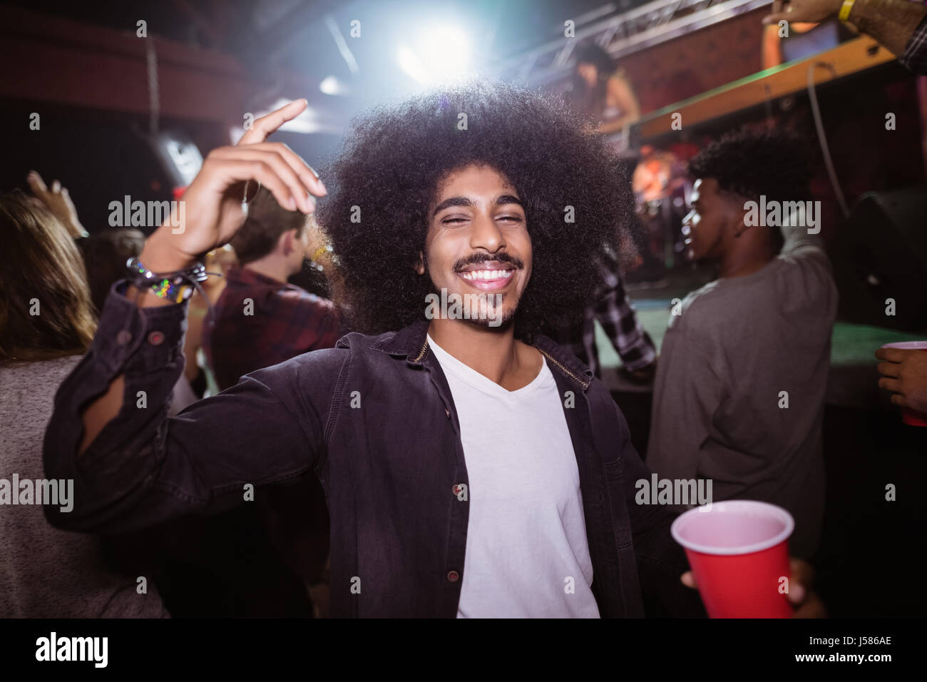 Happy man with drink dancing while standing in nightclub Stock Photo ...