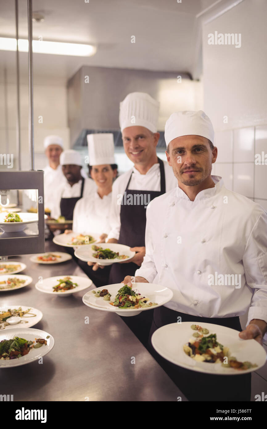 Portrait of chefs presenting food plates in the commercial kitchen ...