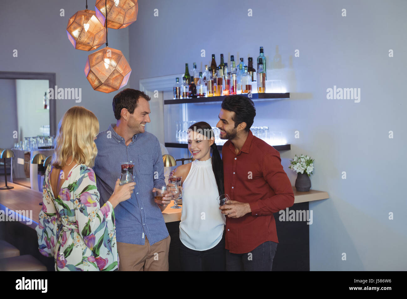 Two couples having cocktails together in bar restaurant Stock Photo - Alamy