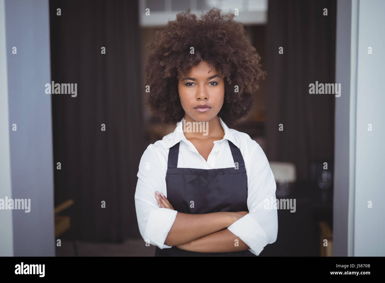 Portrait of confident waitress standing with arms crossed in restaurant ...