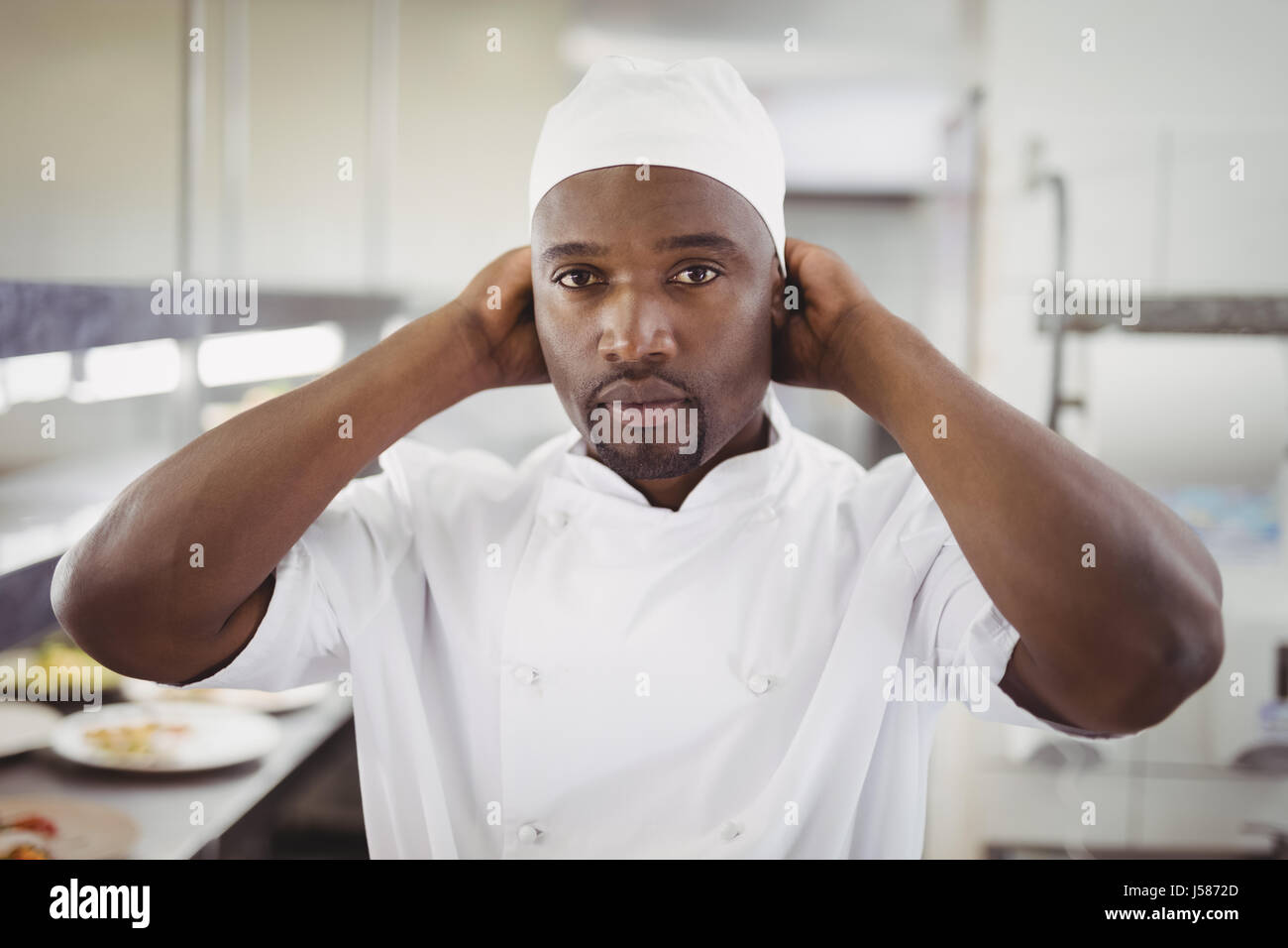Portrait of smiling chef wearing chefs hat in commercial kitchen at ...