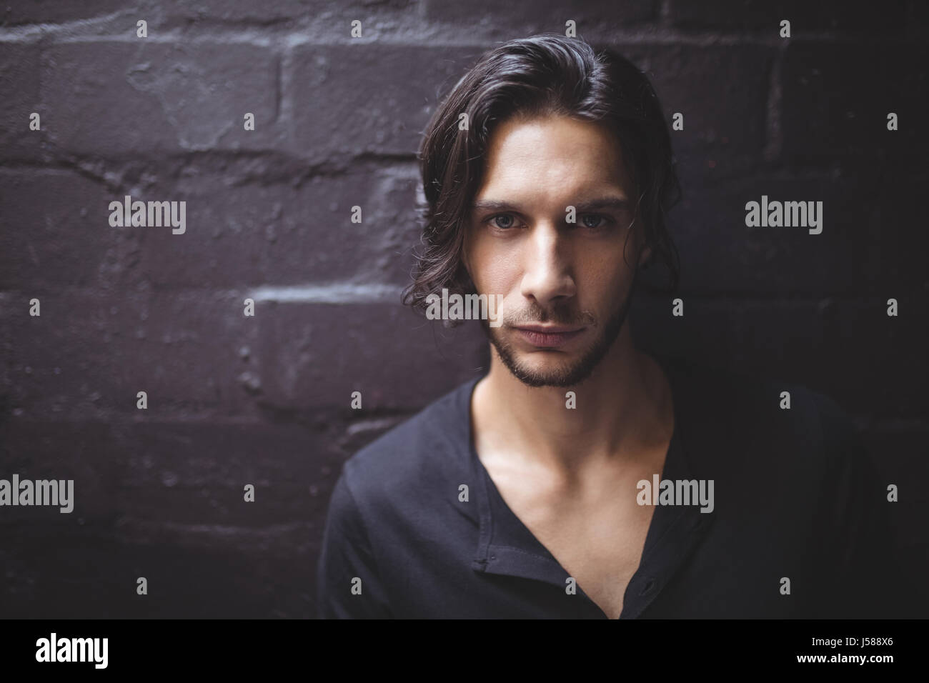 Portrait of young man standing against wall Stock Photo - Alamy
