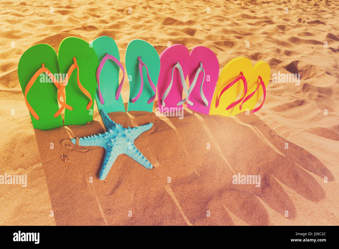 Summer beach fun - set of family sandals in sand on beach, retro toned ...