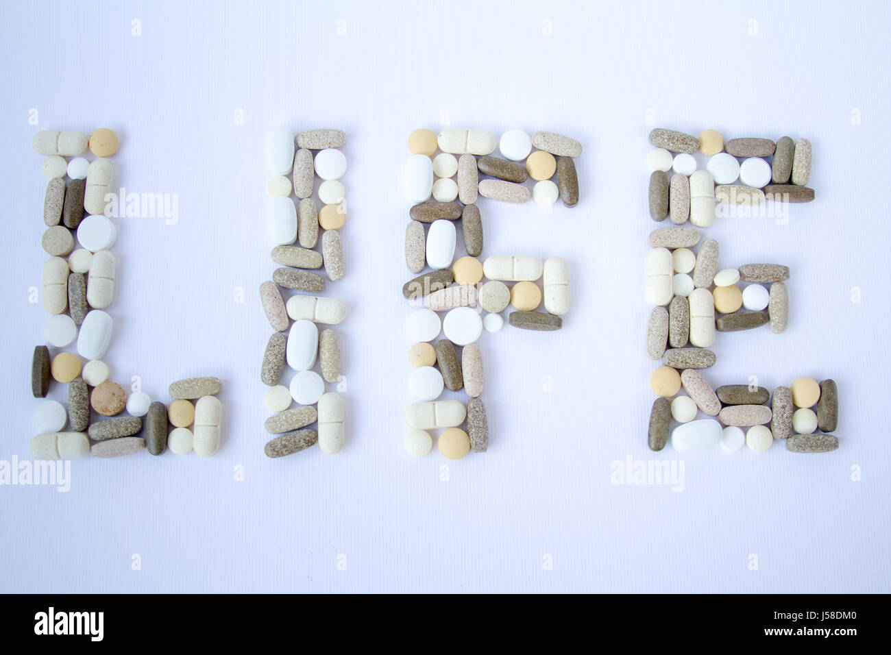 The word LIFE laid out on a white background with medical tablets of ...
