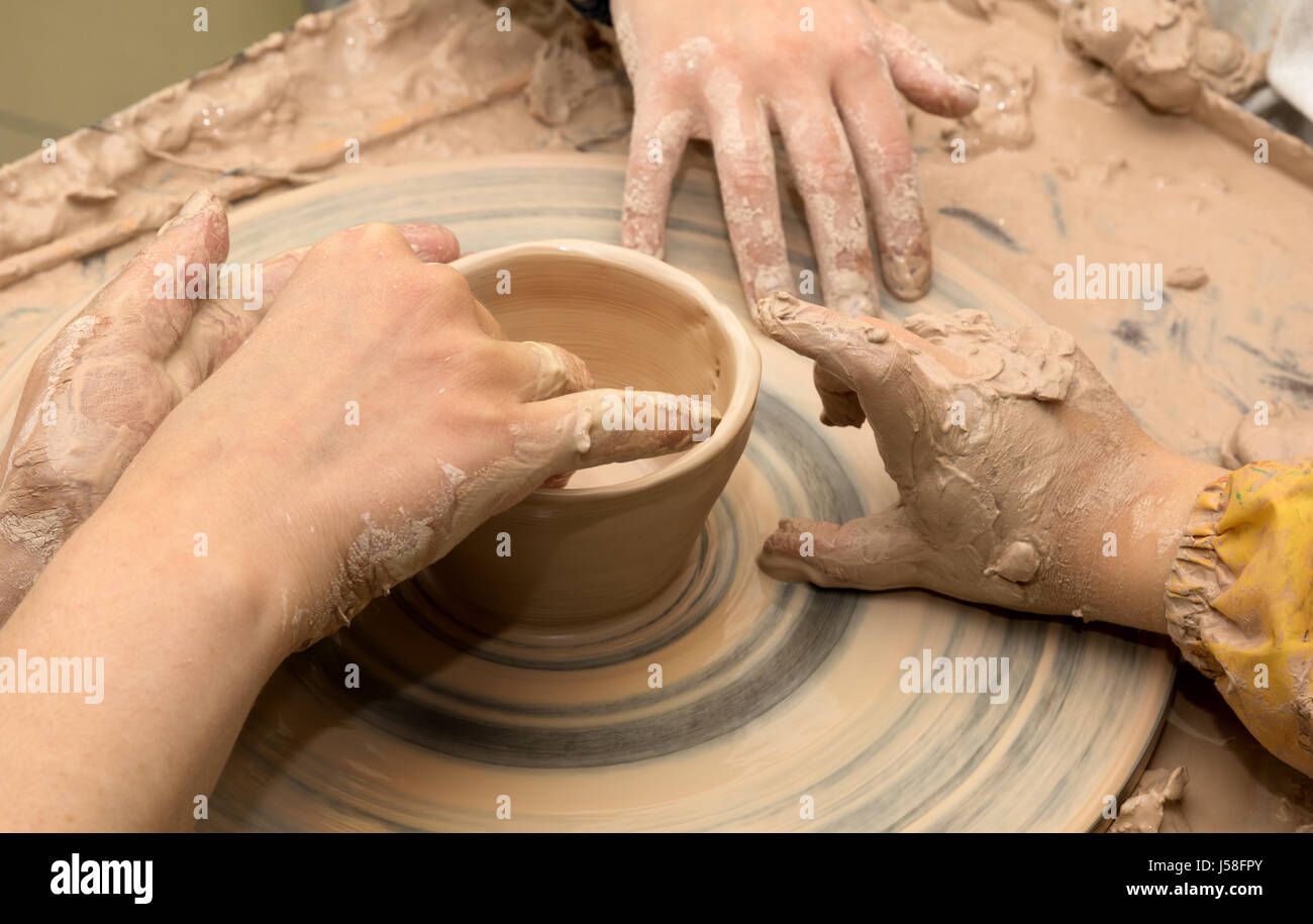 Beginner and teacher hands in clay at process of making crockery on ...
