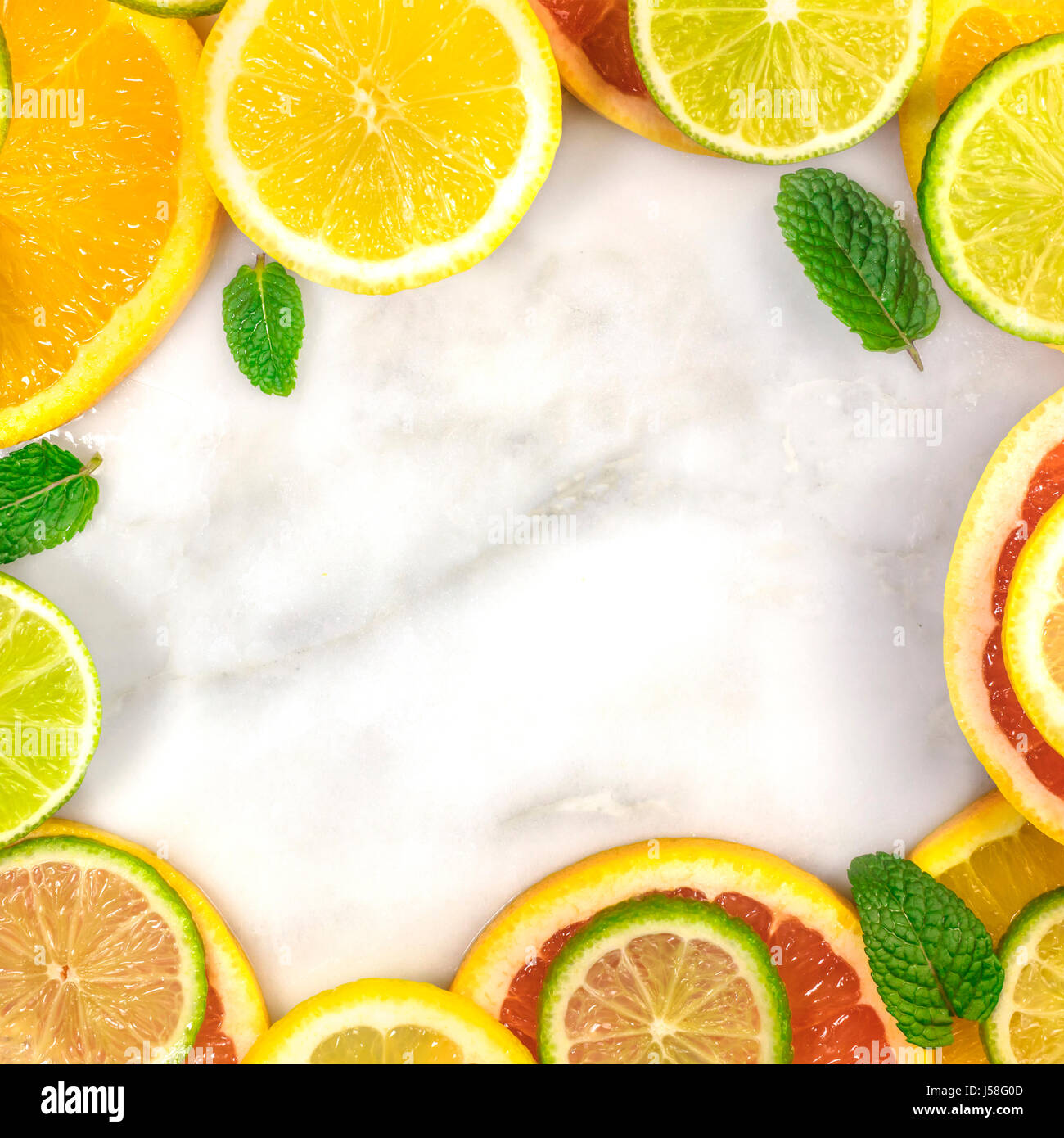 A vibrant square frame of juicy citrus fruits, on a white marble ...