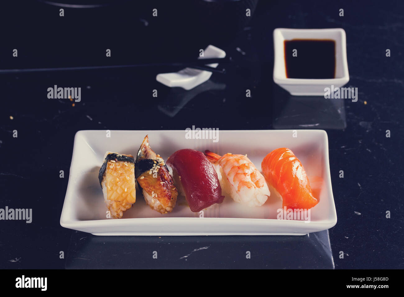 Row of japanese sushi dish in white plate on black background, retro ...