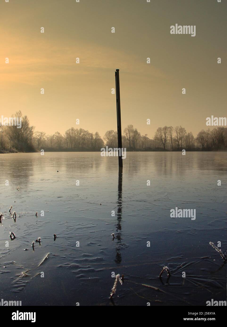 winter cold mirroring ice frozen sheet of ice evening light pole post ...
