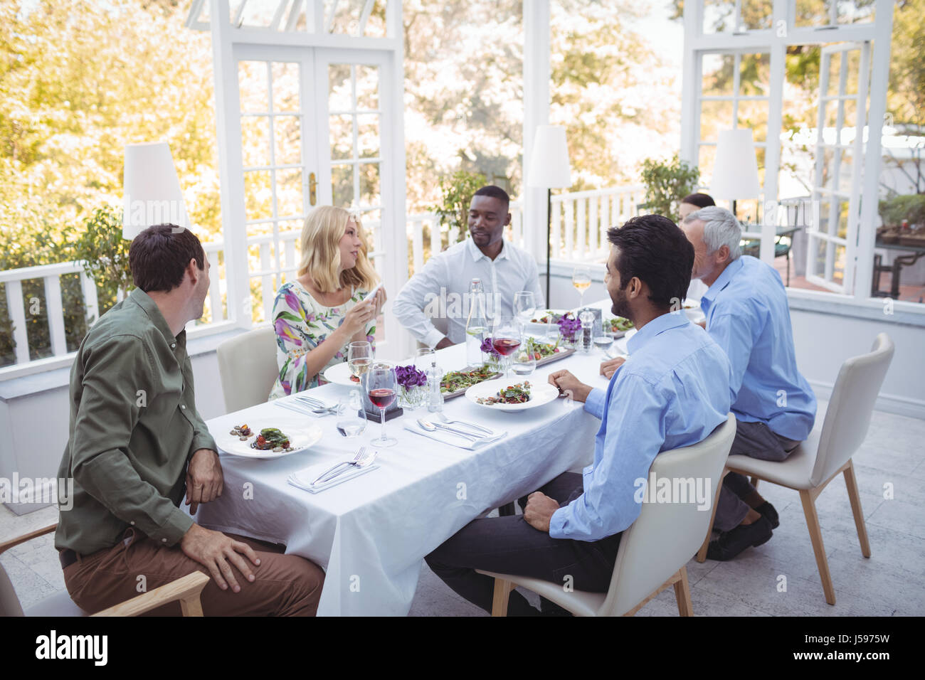 Group of friends interacting with each other while having meal together ...