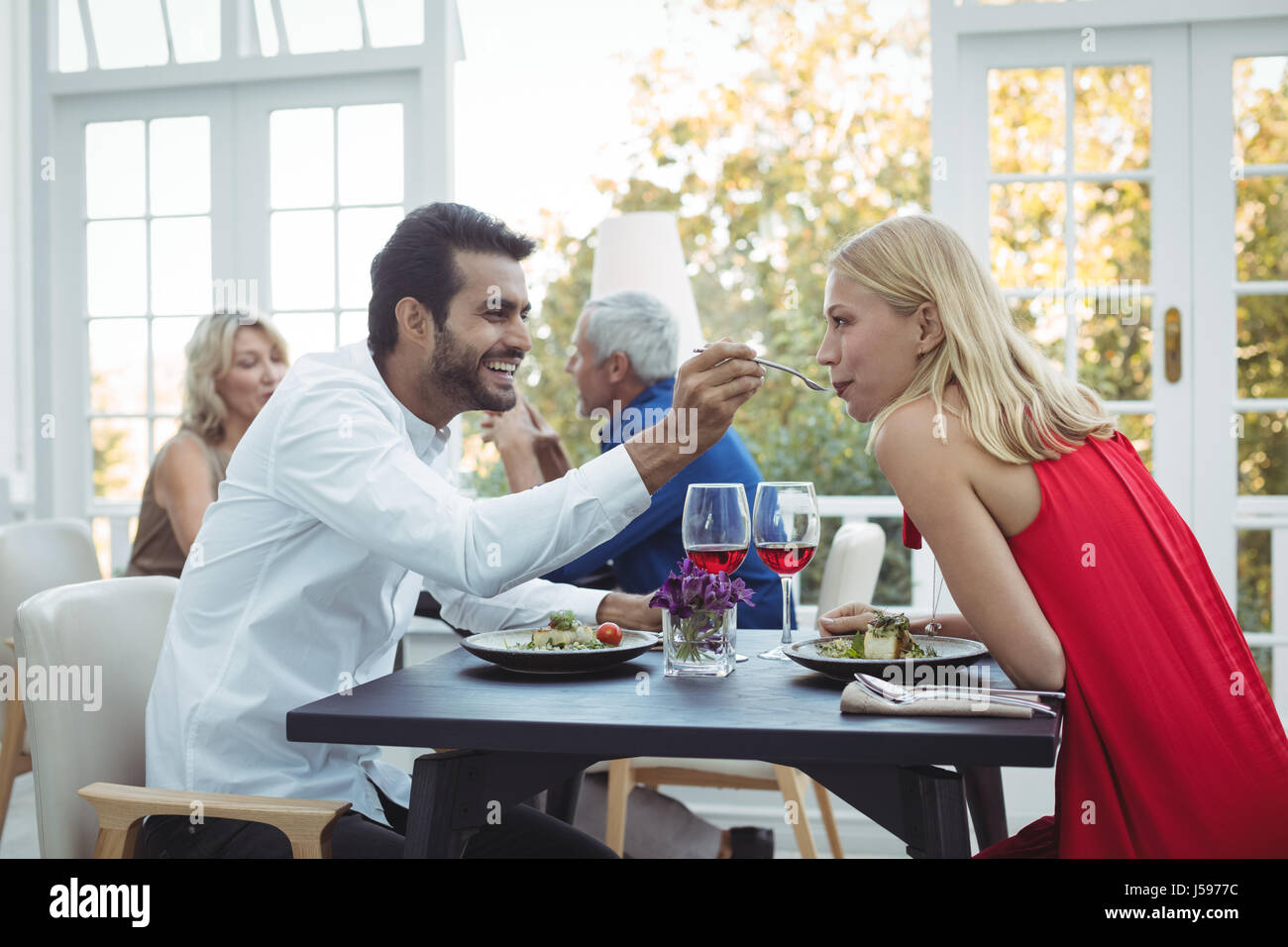 Affectionate man feeding woman in restaurant Stock Photo - Alamy