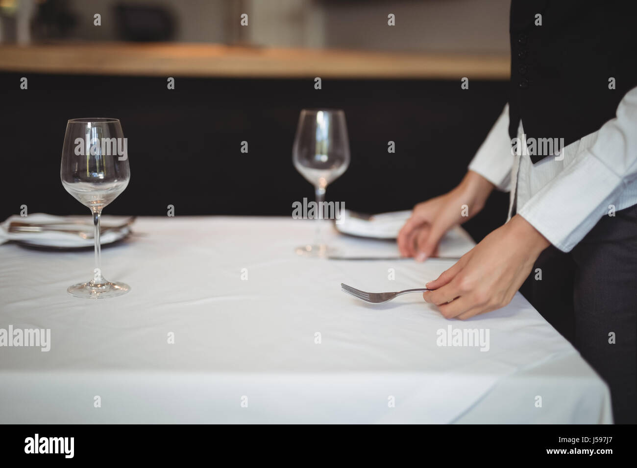 Mid-section of waitress setting table in restaurant Stock Photo - Alamy