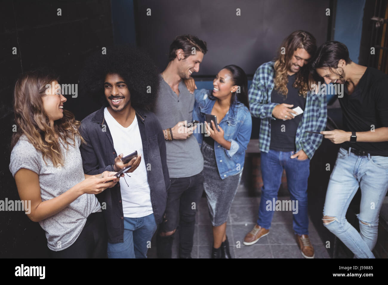 Cheerful friends using mobile phone while standing together Stock Photo ...