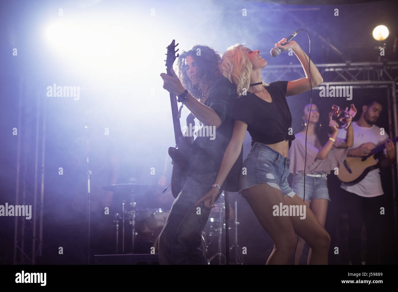 Young female singer with male guitarist performing together at ...