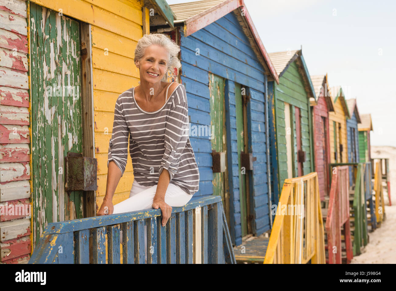 Portrait smiling woman sitting on railing of hut at beach Stock Photo ...