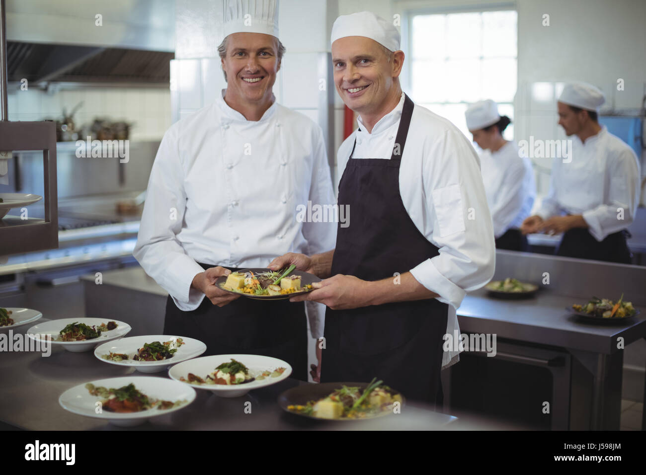 Portrait of chefs presenting his food plates in the commercial kitchen ...