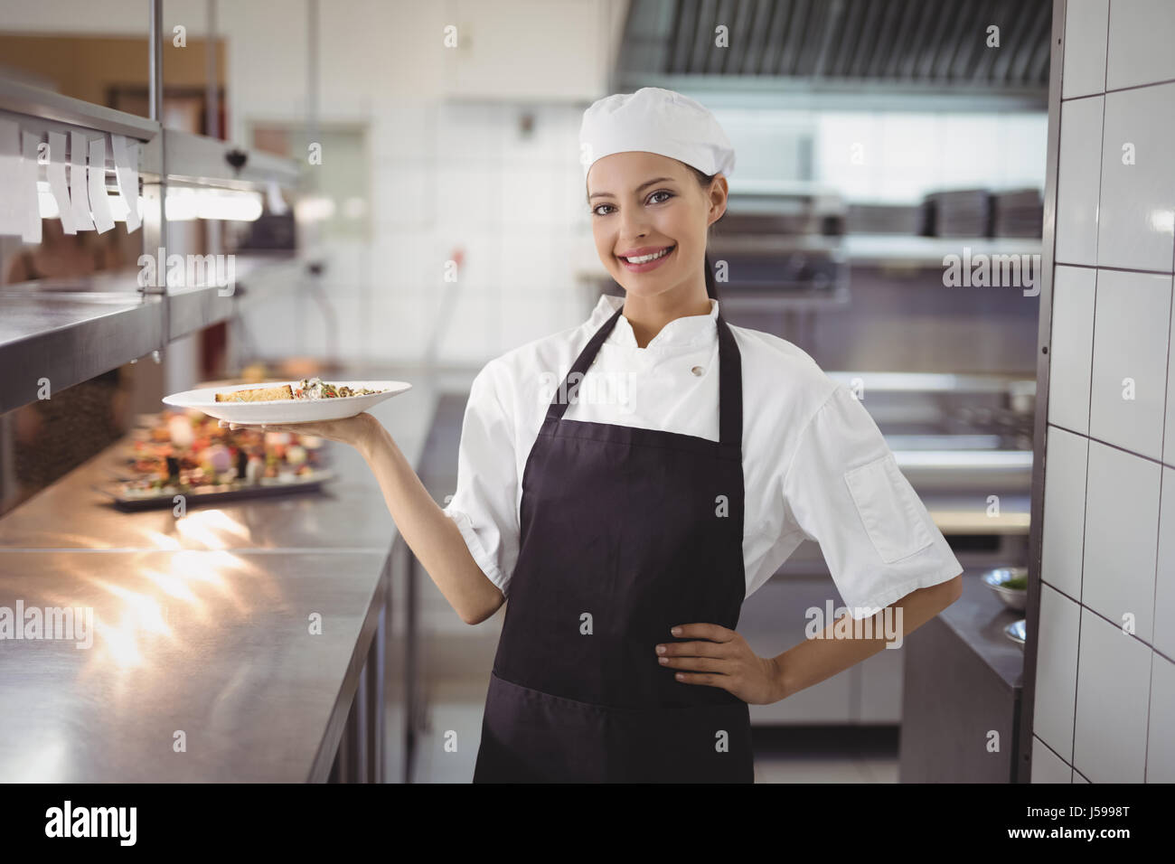 Female chef showing food dish to the camera in the commercial kitchen ...